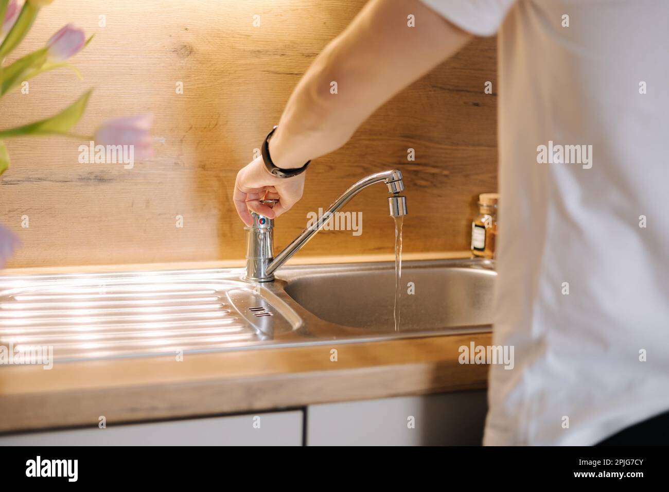 Back view of man turns on the water in the kitchen Stock Photo - Alamy
