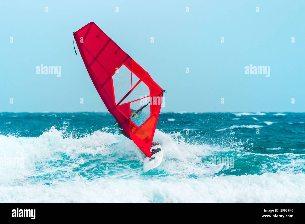 windsurfer riding the wave with a white board and red sail Stock Photo ...