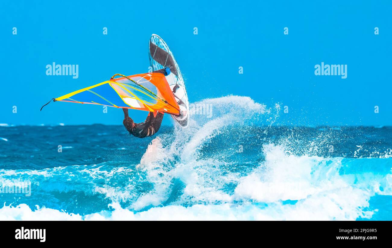 summer sports: windsurfer making an acrobatic jump in the waves and ...