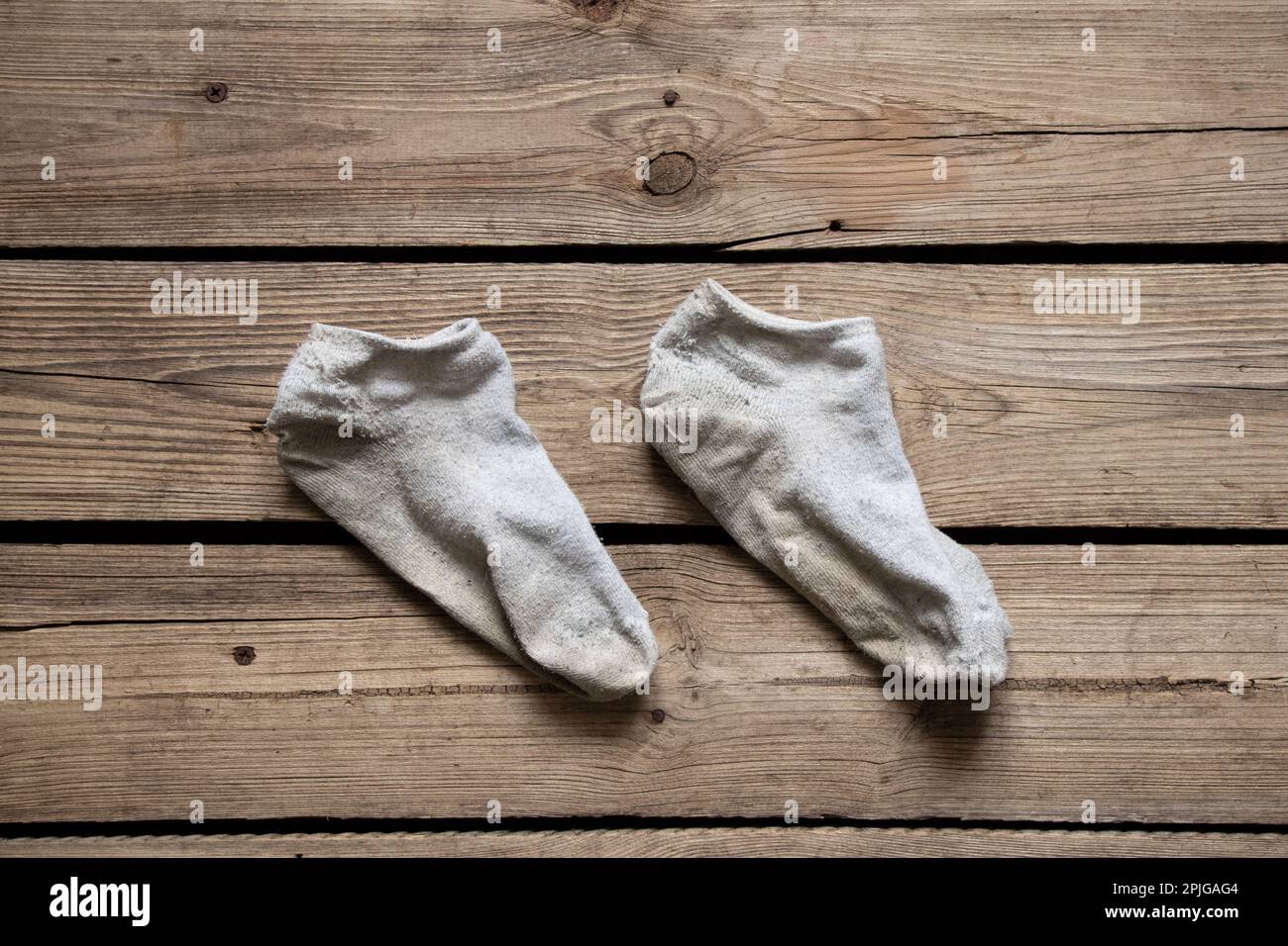 Dirty short white socks lie on the wooden floor of the house close-up ...