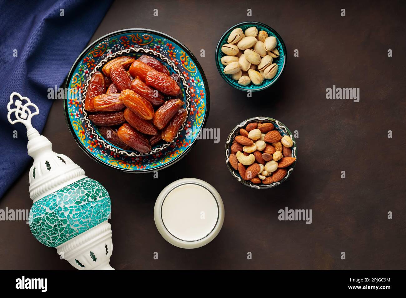 Ramadan Kareem food and drinks. Date fruits, nuts and milk on a dark ...