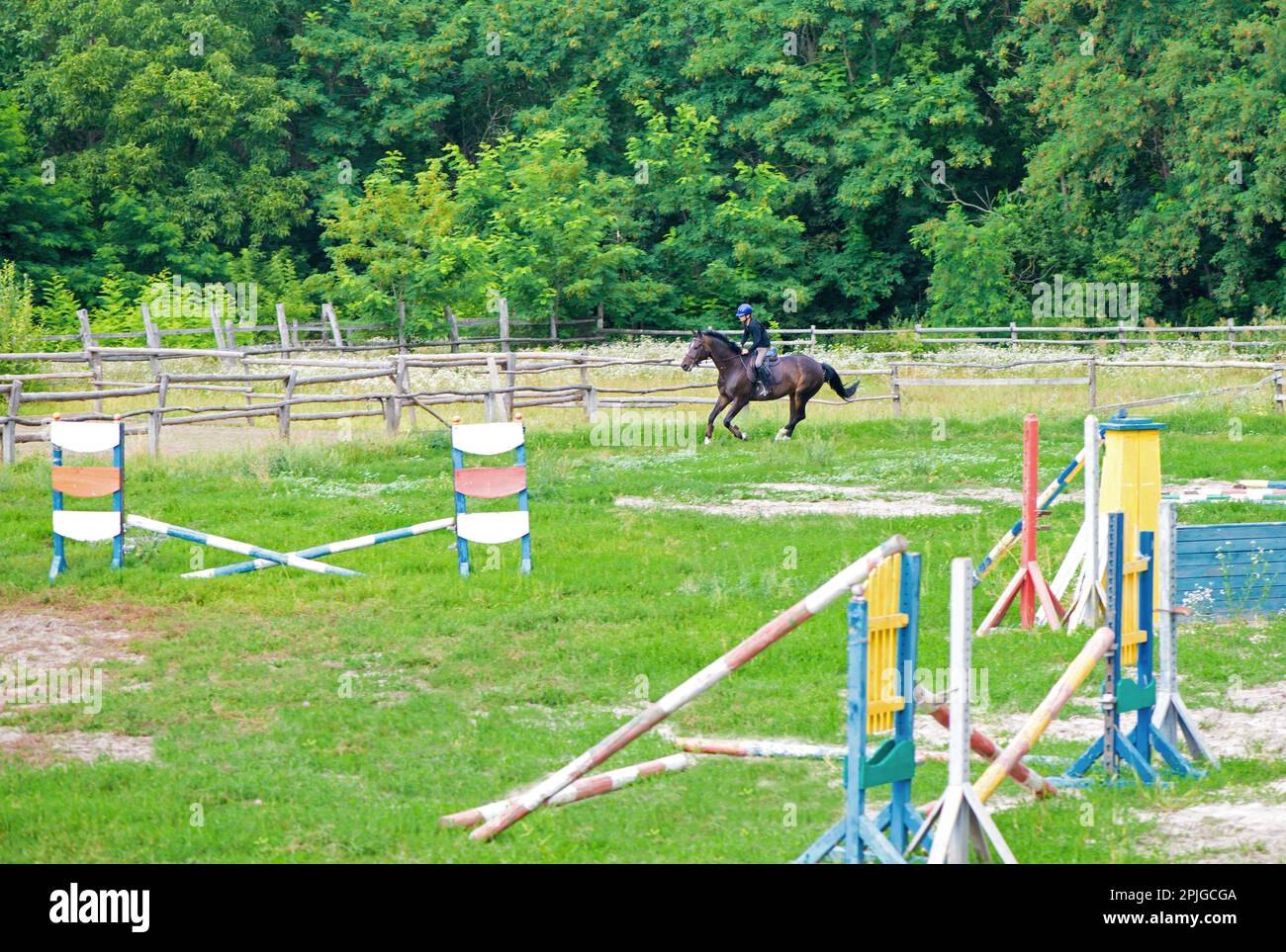 Young rider on horse jumping over obstacle on her course in competition ...