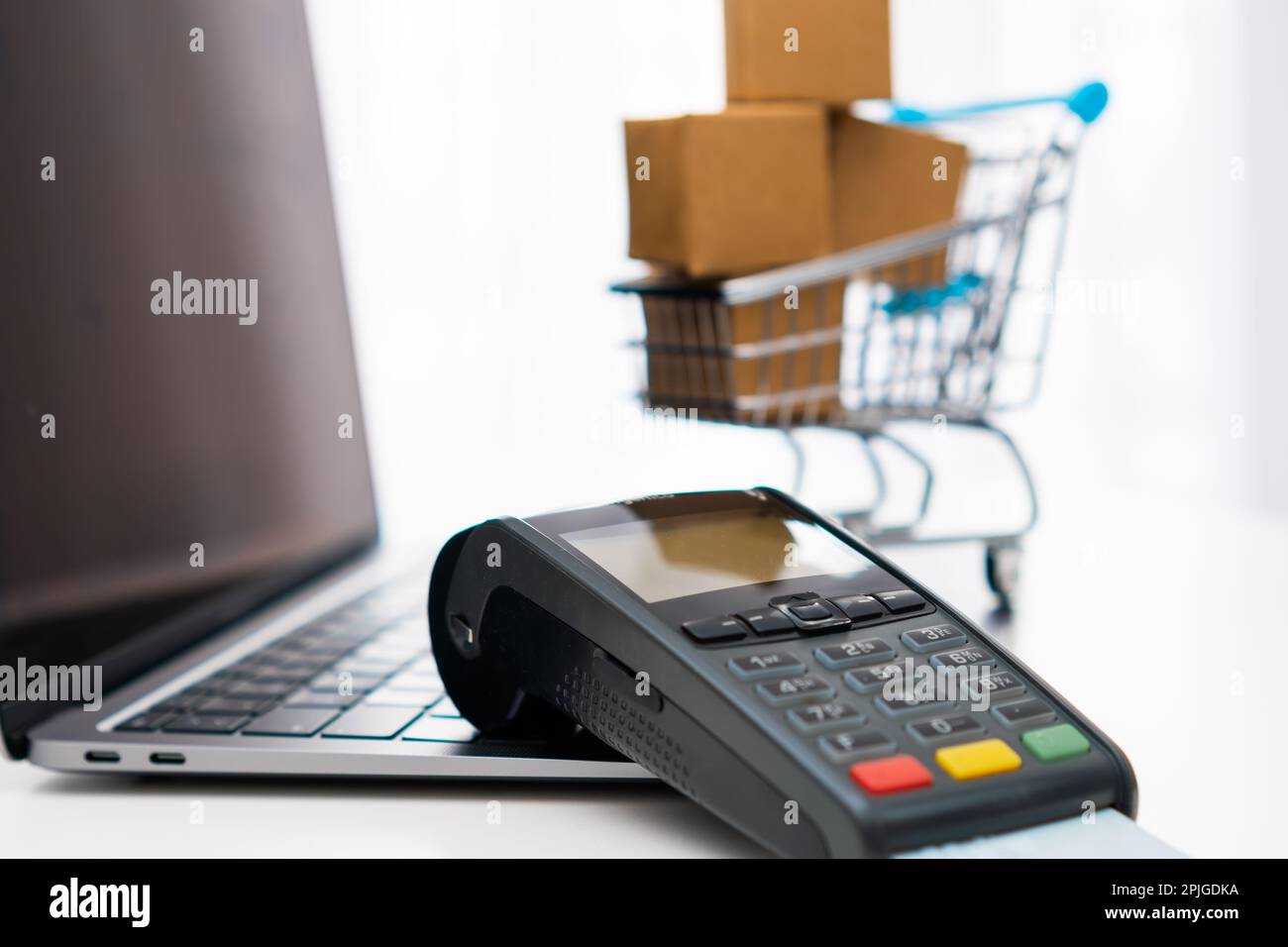 Paying terminal on the laptop and toy shopping cart with cardboard ...