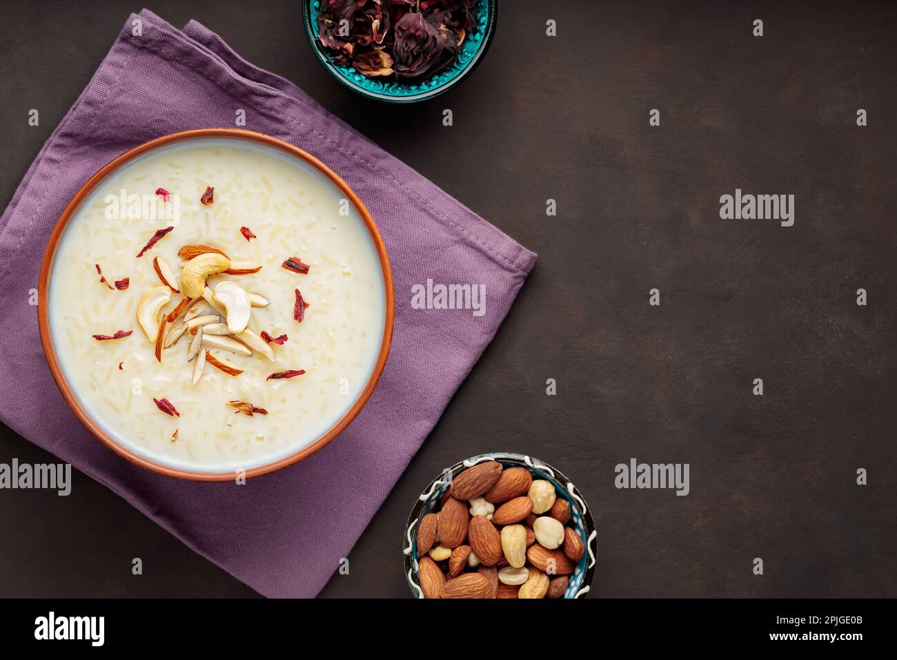 Rice kheer, nuts and dried hibiscus flowers on a dark background ...