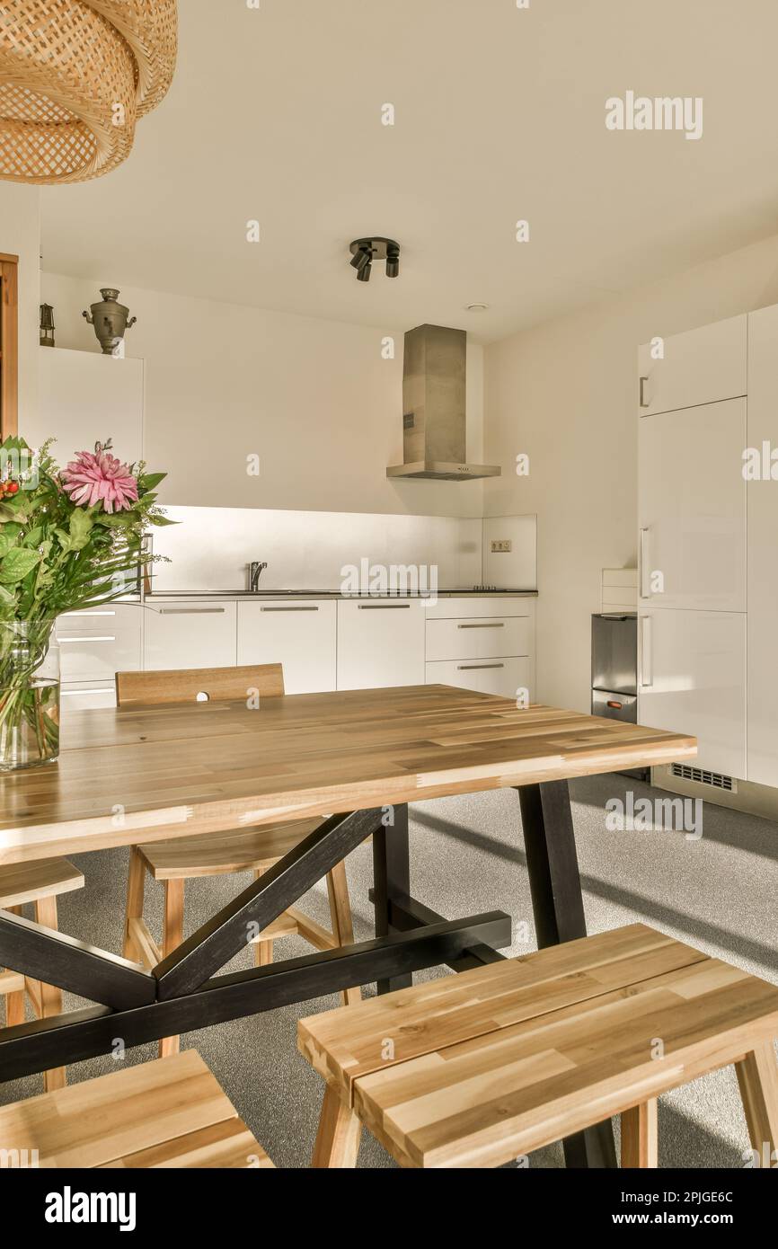 a dining table and bench in a kitchen with white cupboards behind it ...