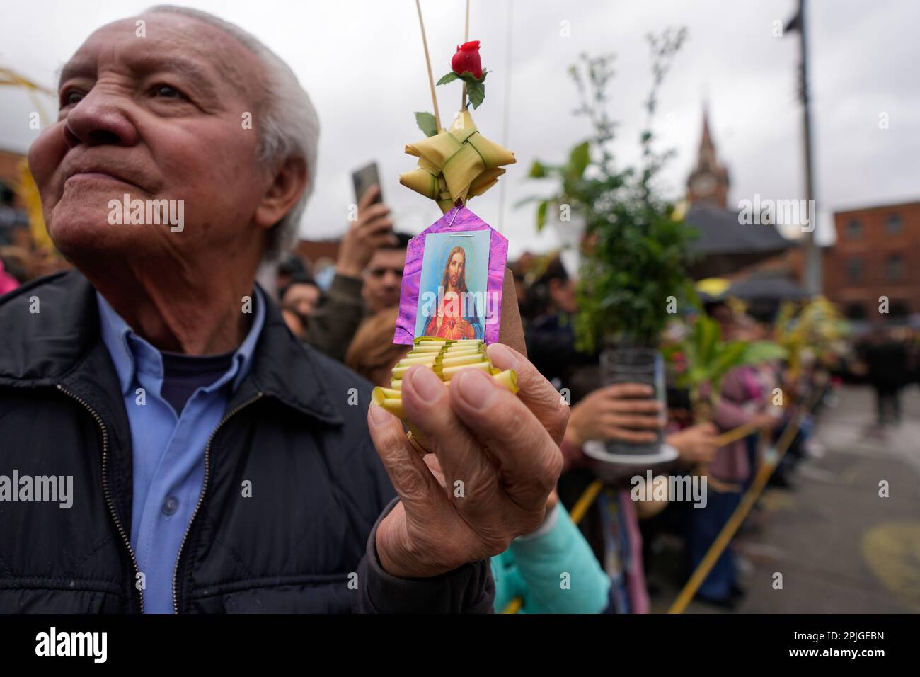 A man holds a palm frond to be blessed during an outdoor Palm Sunday ...