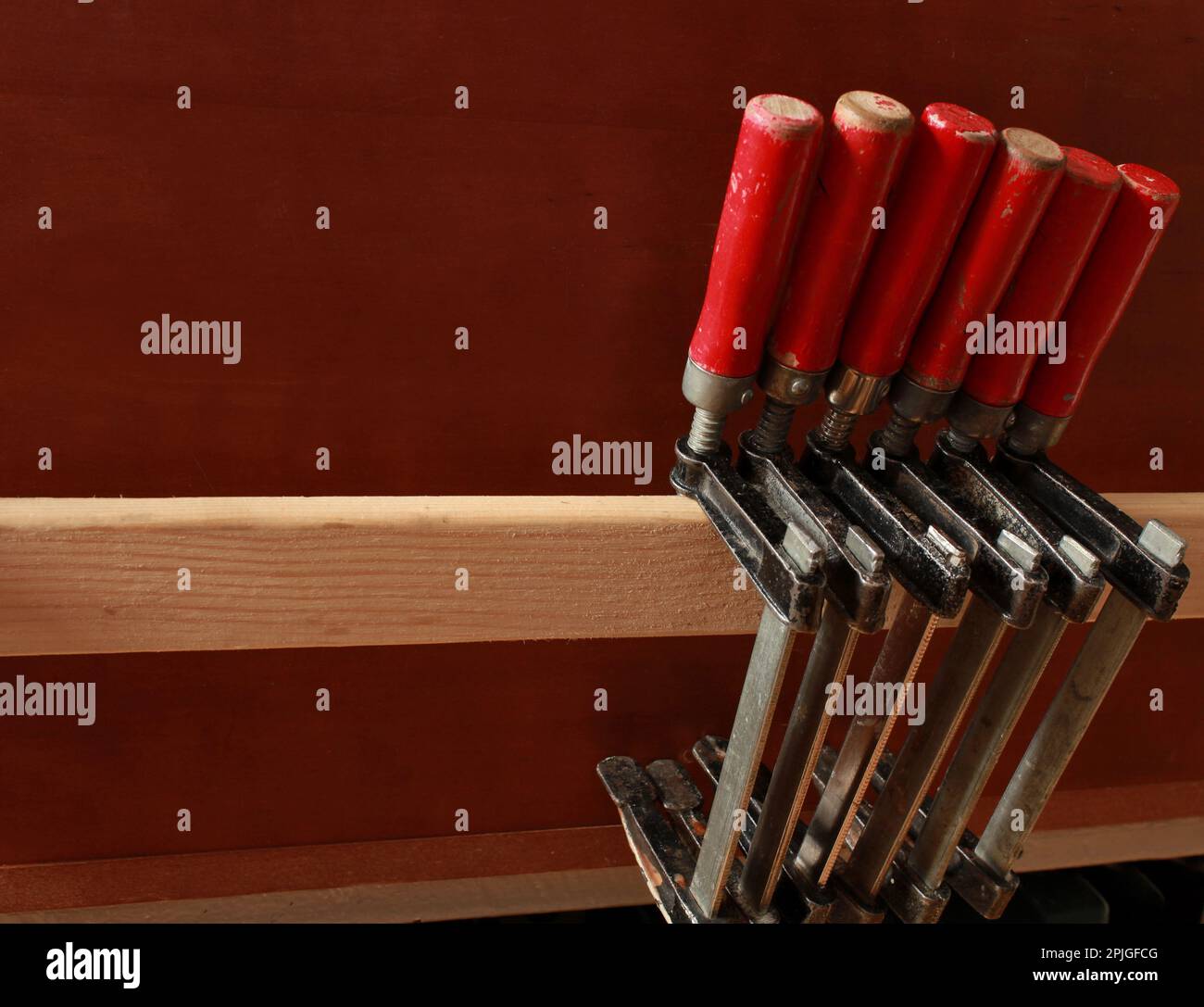 carpentry clamps with red handles hang on a shelf in a carpentry ...
