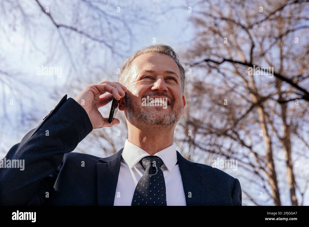 Business man in a suit calling someone, blue sky background, the ...