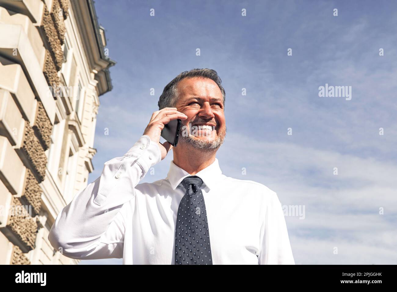 Business man in a suit calling someone, blue sky background, the ...
