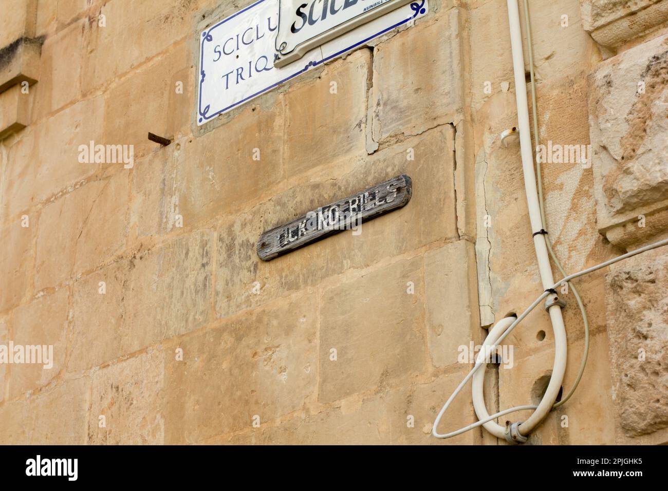 Weather worn Stick no bills sign on a sandstone wall in Malta Stock ...