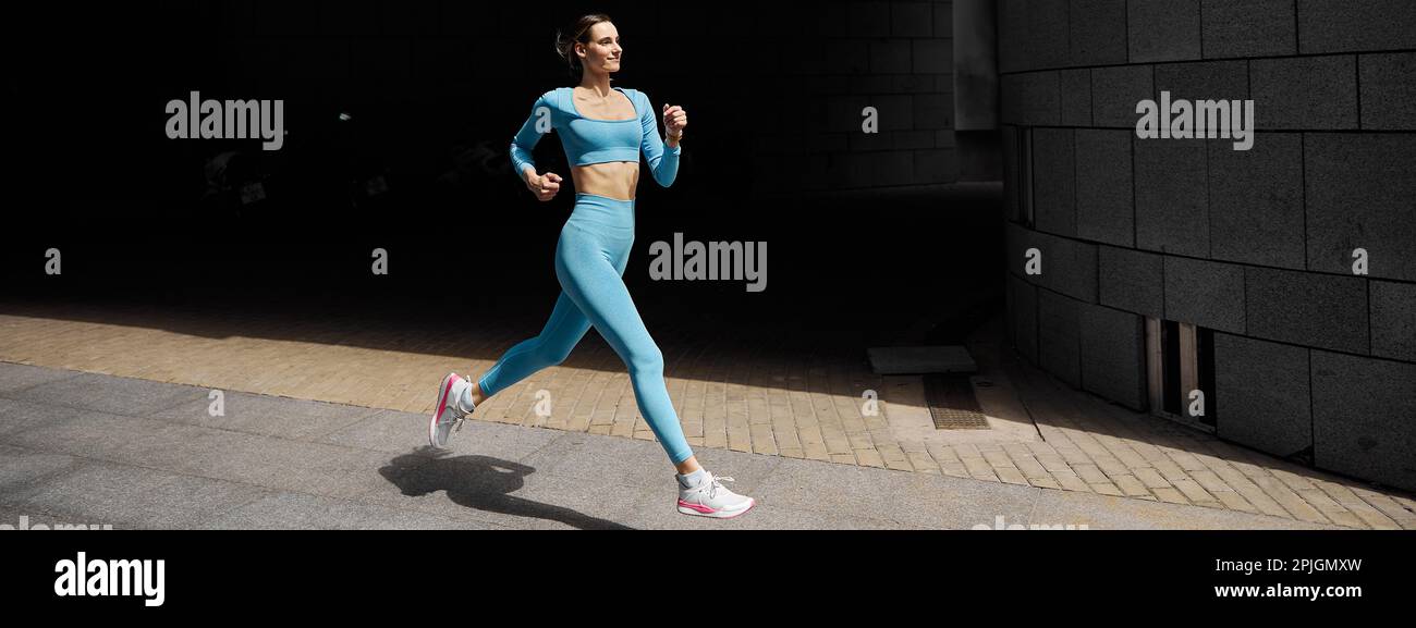 Beautiful fit young woman jogger is running outdoors Stock Photo - Alamy