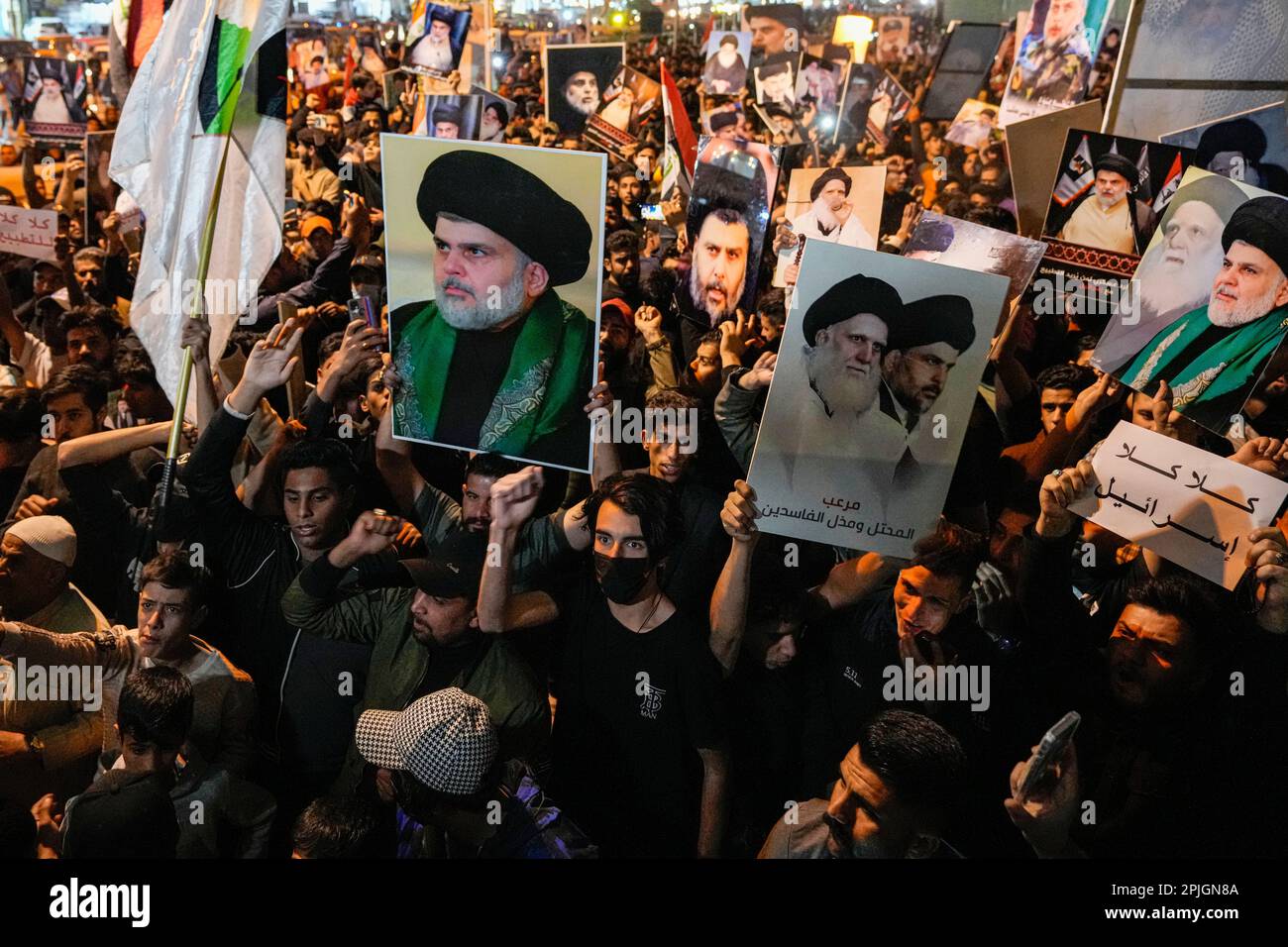Followers of Shiite cleric Muqtada al-Sadr hold posters with his photo ...
