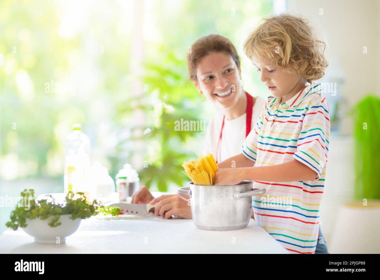 Family cooking dinner. Mom and child cook spaghetti in white sunny ...
