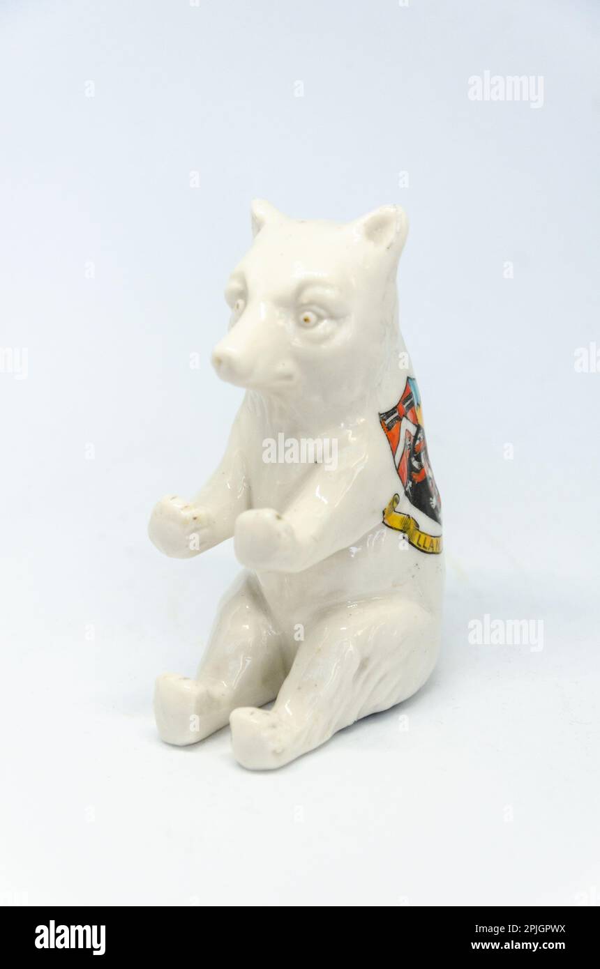 An old, white china bear, a souvenir from Llangollen isolated against a ...