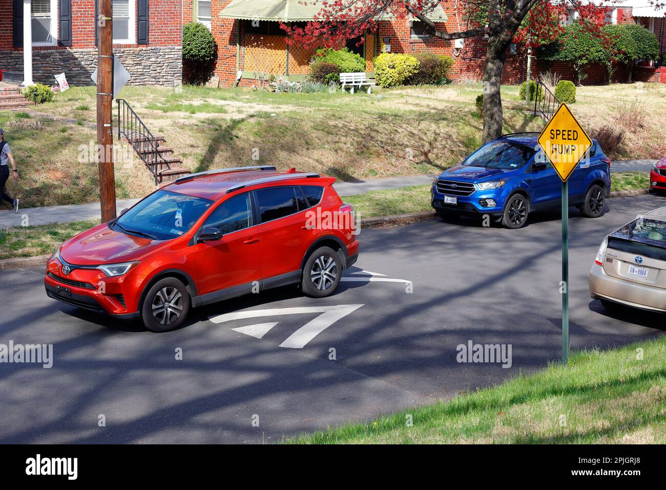 A red car goes over a speed bump, speed hump. Speed humps are designed ...