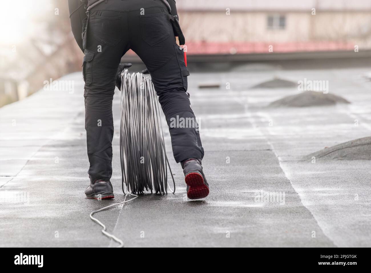 Ground wire. A worker lays a ground cable on the roof of a building ...