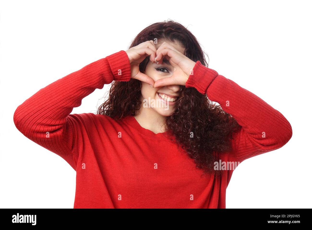 girl peeking through hands making heart shape hand sign love symbol ...