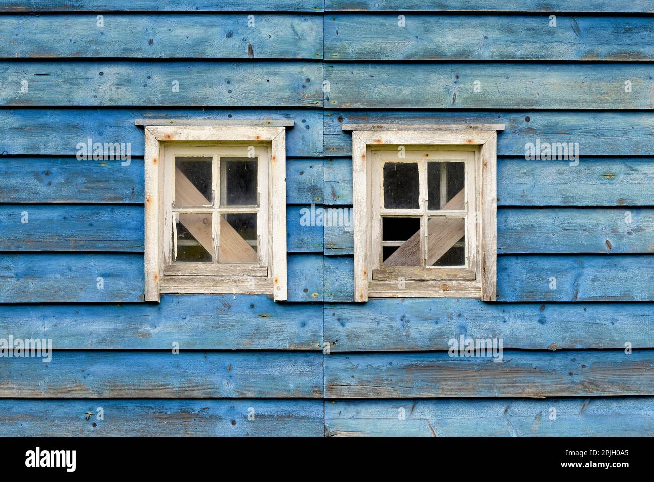 Abandoned wooden house, blue boarded facade with white barricaded ...