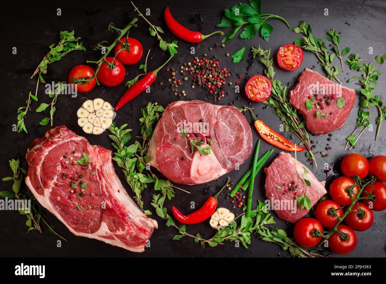 Different types of steaks set. Assorted raw meat on a black chalk board ...