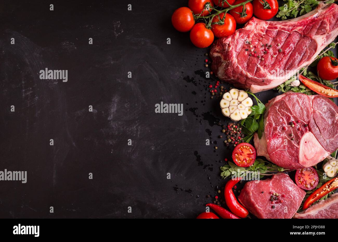 Raw juicy meat steaks ready for roasting on a black chalk board ...