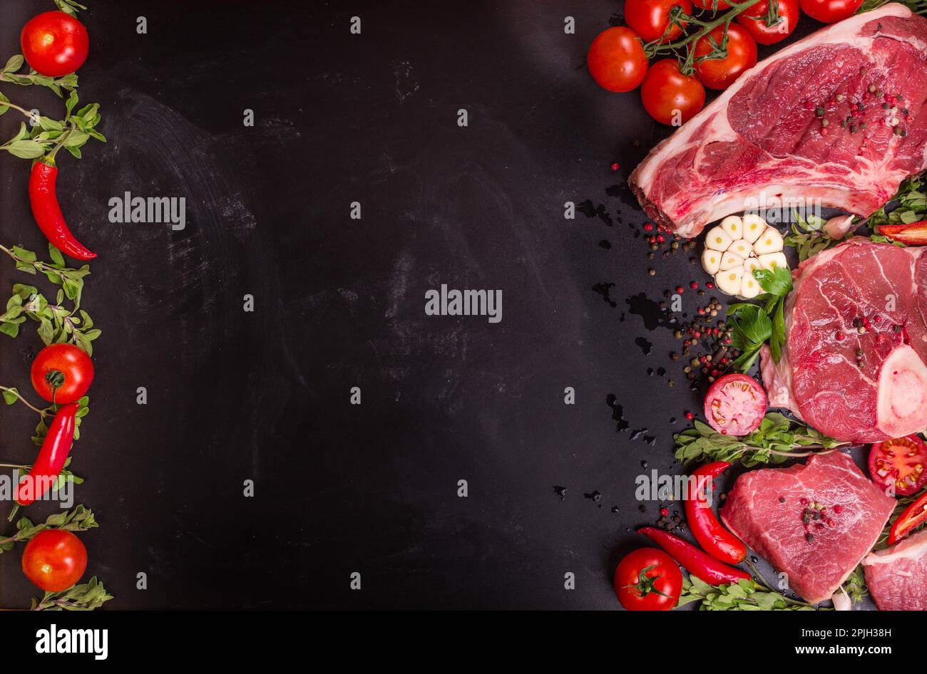 Raw juicy meat steaks ready for roasting on a black chalk board ...