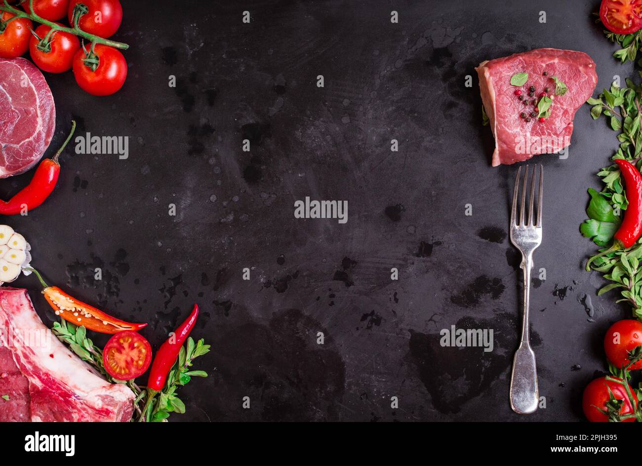 Raw juicy meat steaks ready for roasting on a black chalk board ...