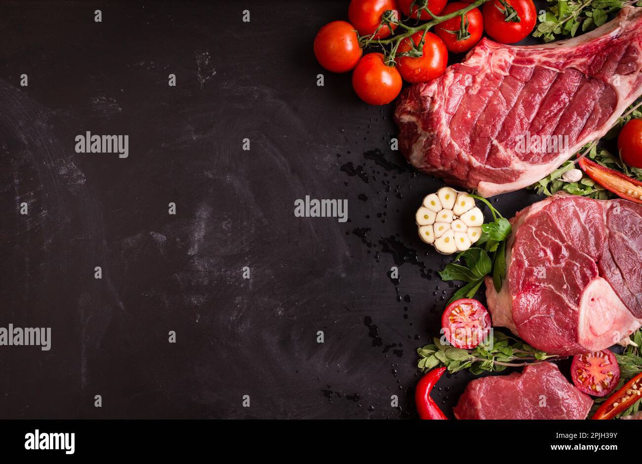 Raw juicy meat steaks ready for roasting on a black chalk board ...