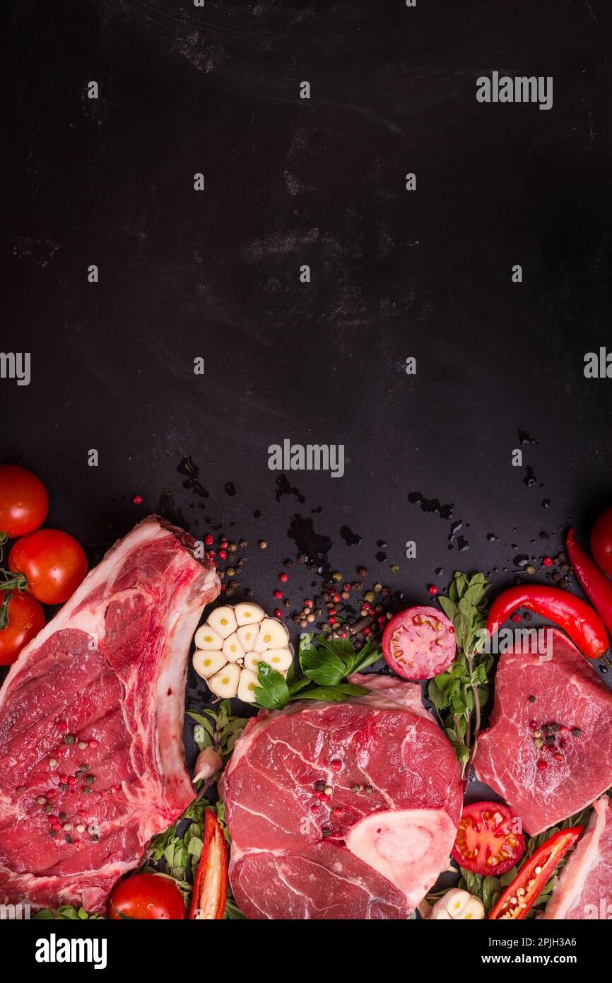 Raw juicy meat steaks ready for roasting on a black chalk board ...