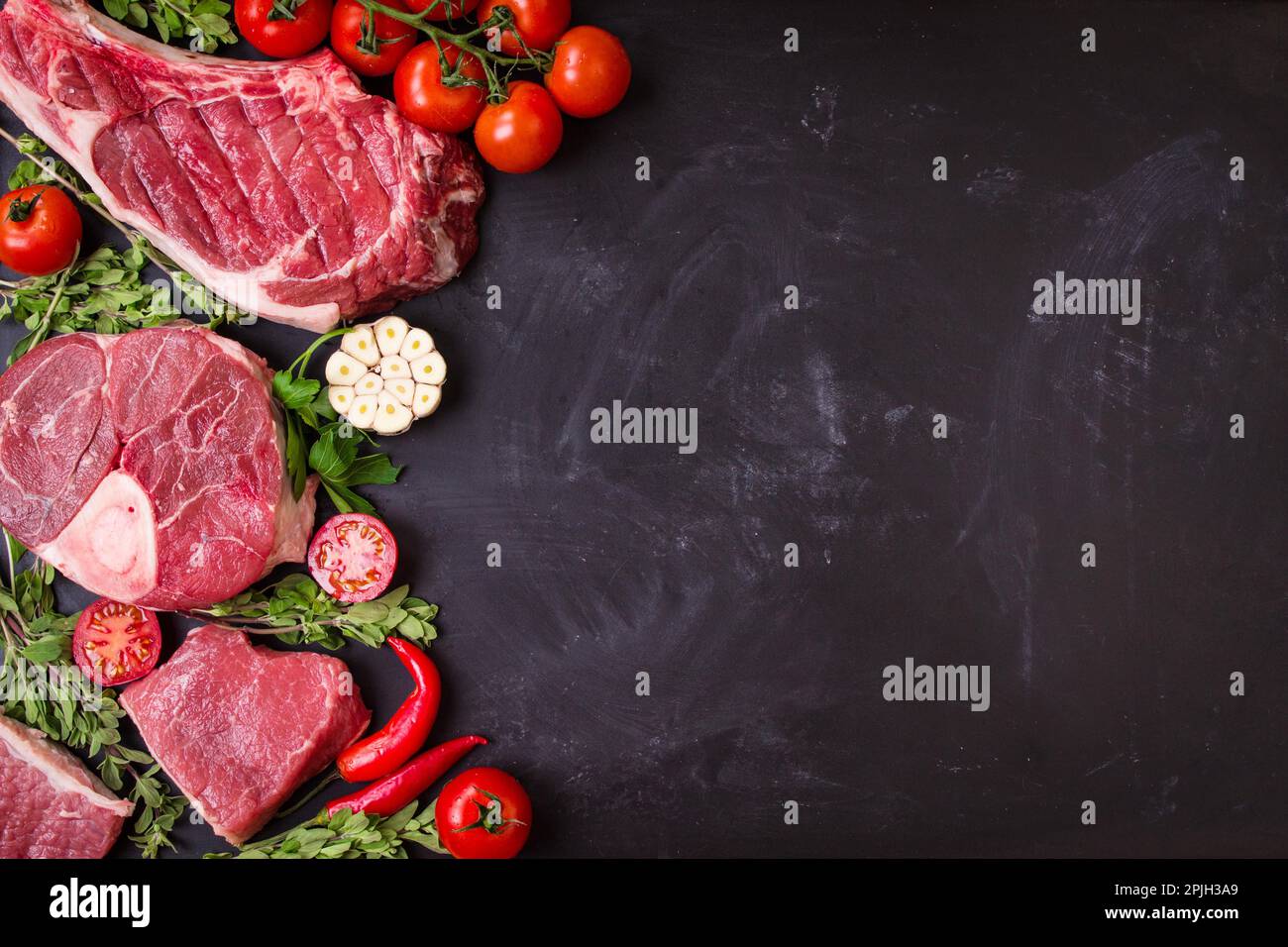 Raw juicy meat steaks ready for roasting on a black chalk board ...