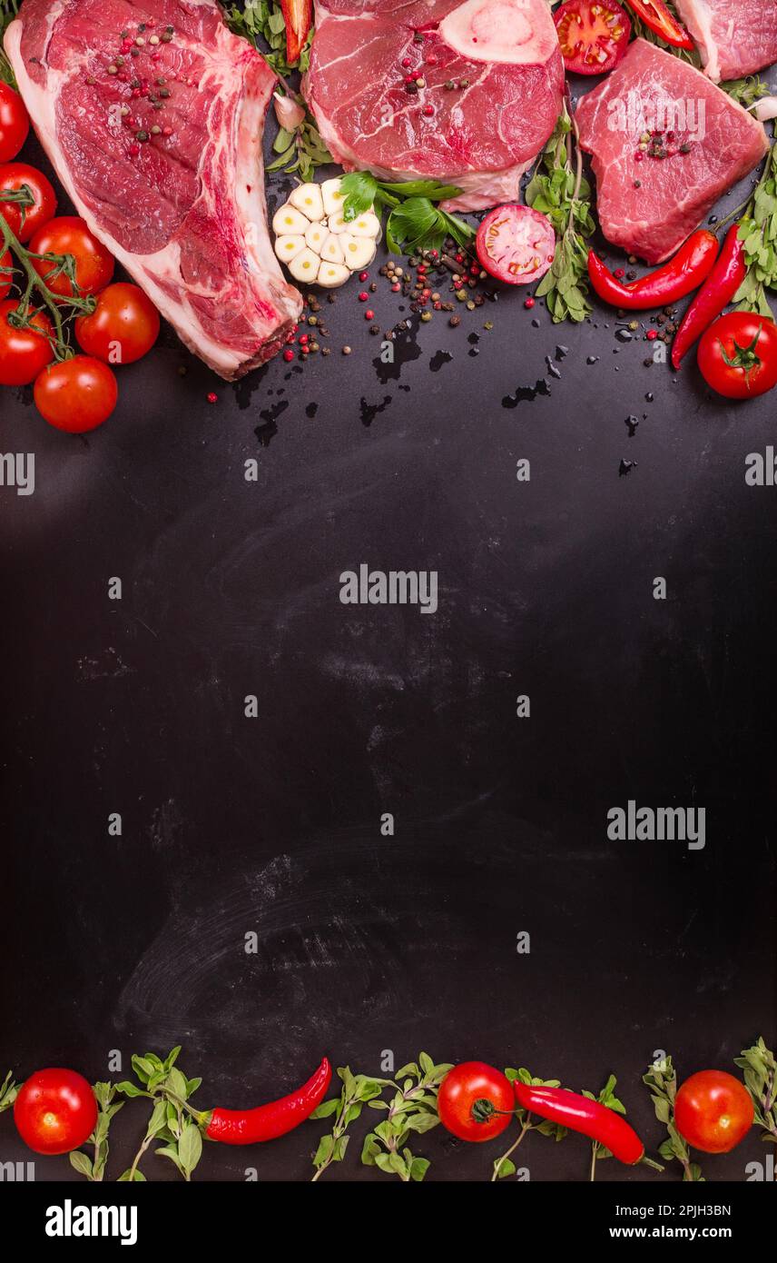 Raw juicy meat steaks ready for roasting on a black chalk board ...