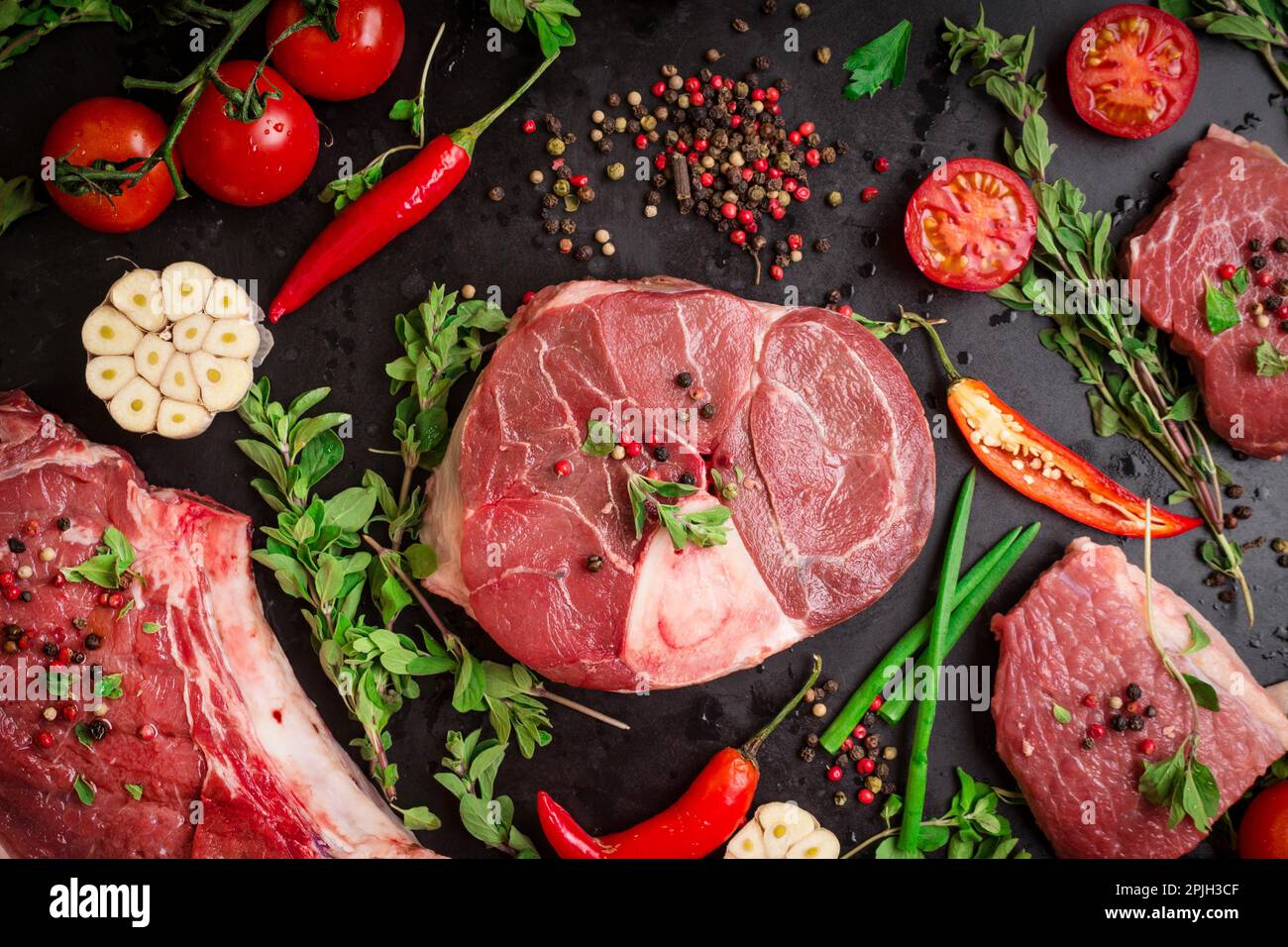 Different types of steaks set. Assorted raw meat on a black chalk board ...