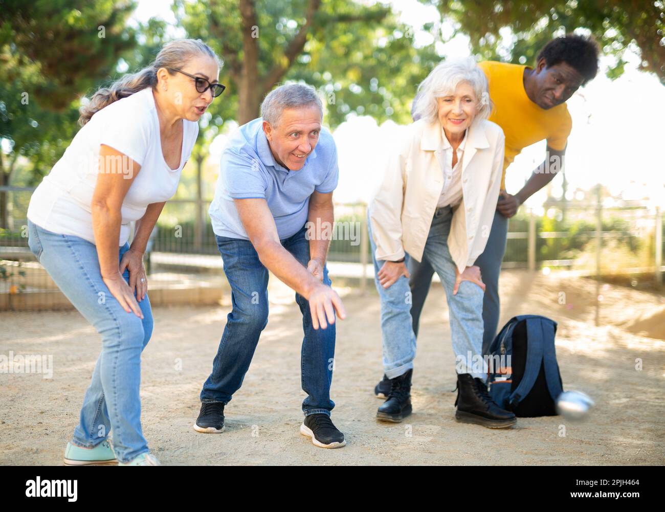 A group of multiracial mature adult people playing patanque game ...