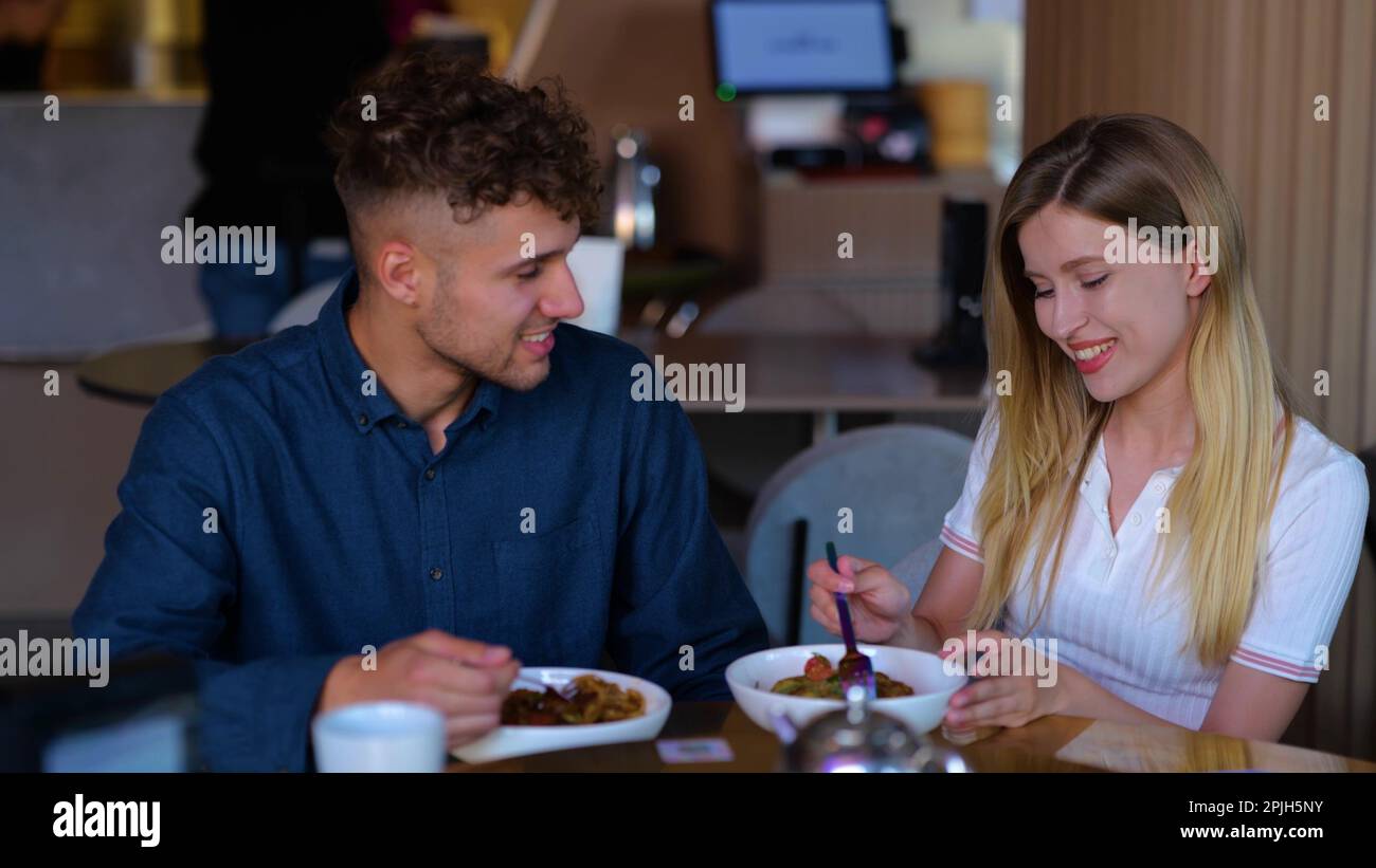 Happy young couple sitting in a cafe. Woman feeding his boyfriend ...