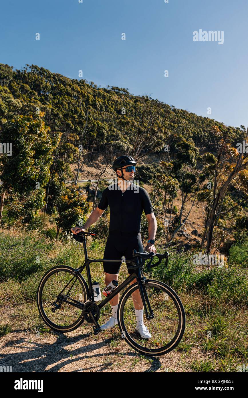 Athlete with his road bike standing in wild terrain looking into the ...