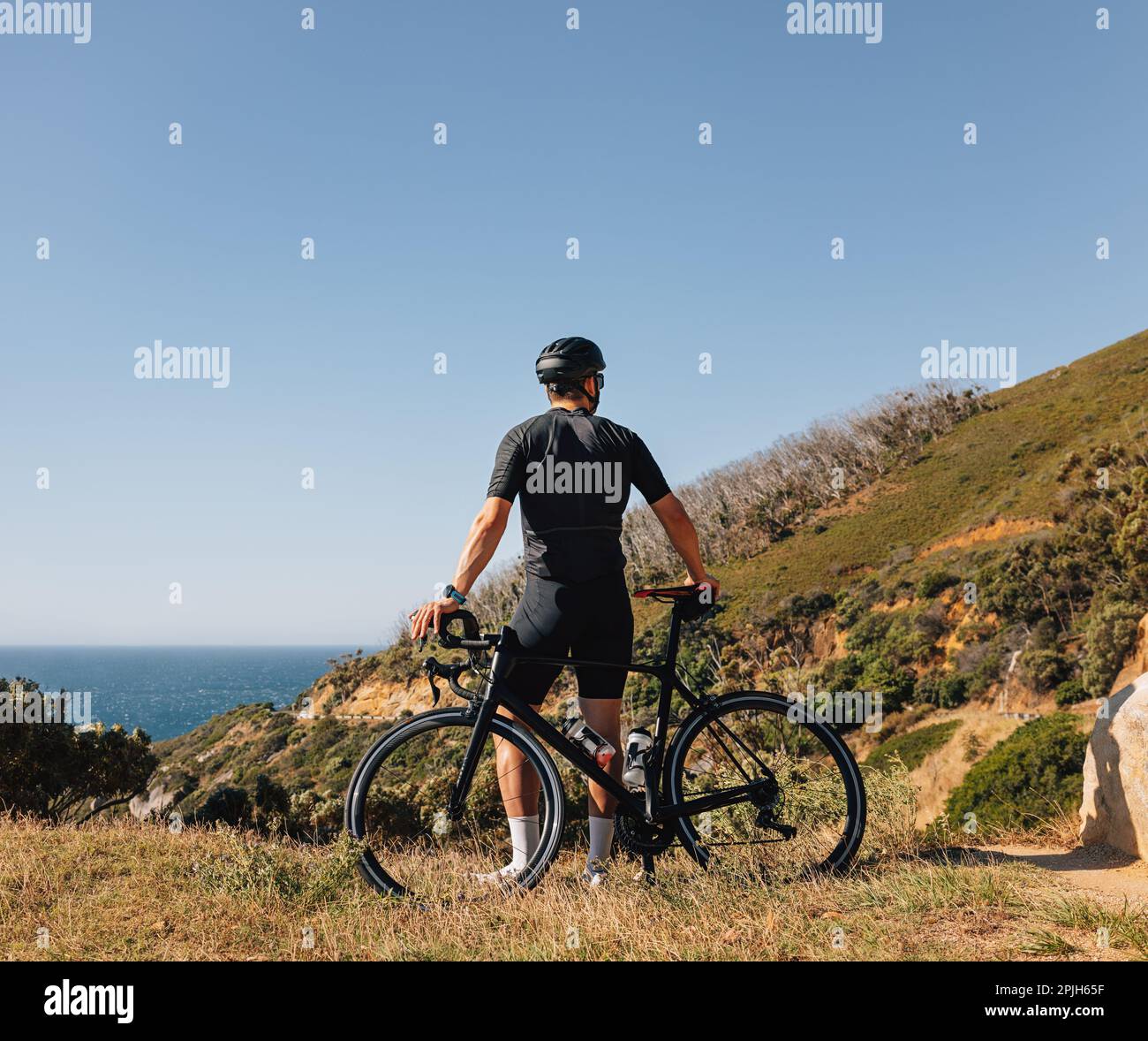 Back view of a male cyclist leaning on his road bike relaxing during ...