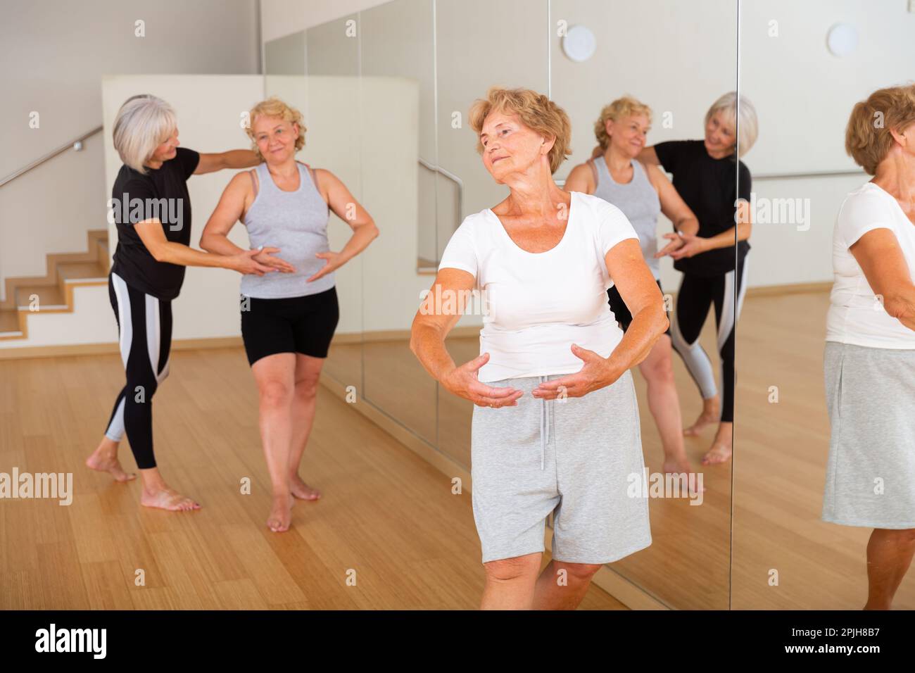 Elderly women stand in the 1st position of the ballet stand, where the ...