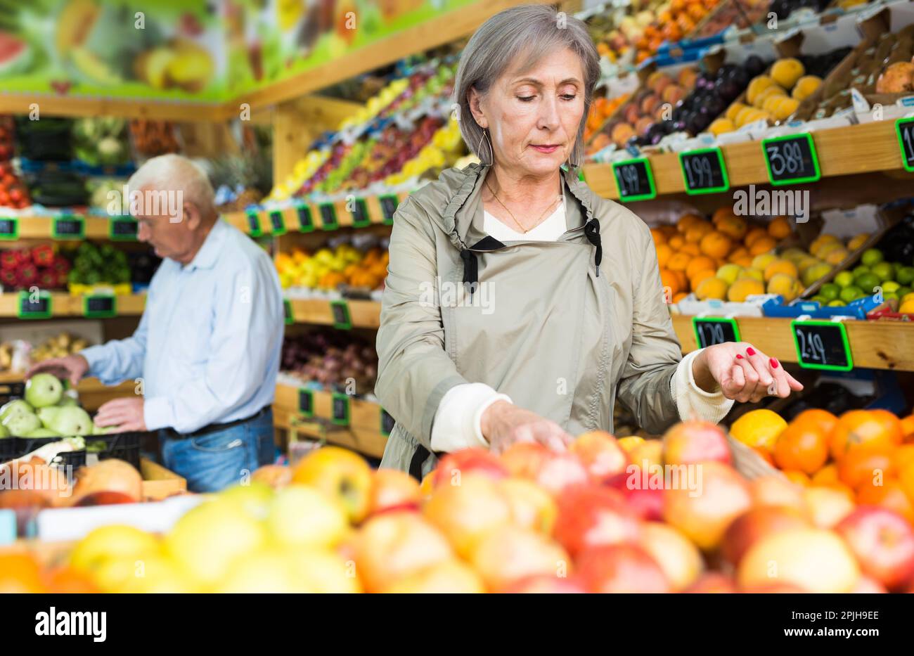 Mature lady choosing fruits in greengrocer Stock Photo - Alamy