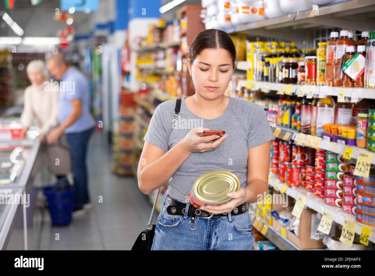 Woman customer scanning barcode on aluminum canned food with smartphone ...