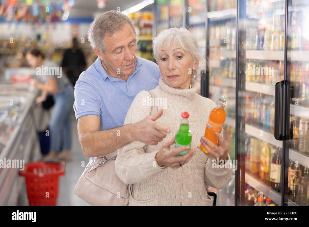 Elderly couple choosing sweet sodas together in the grocery section of ...