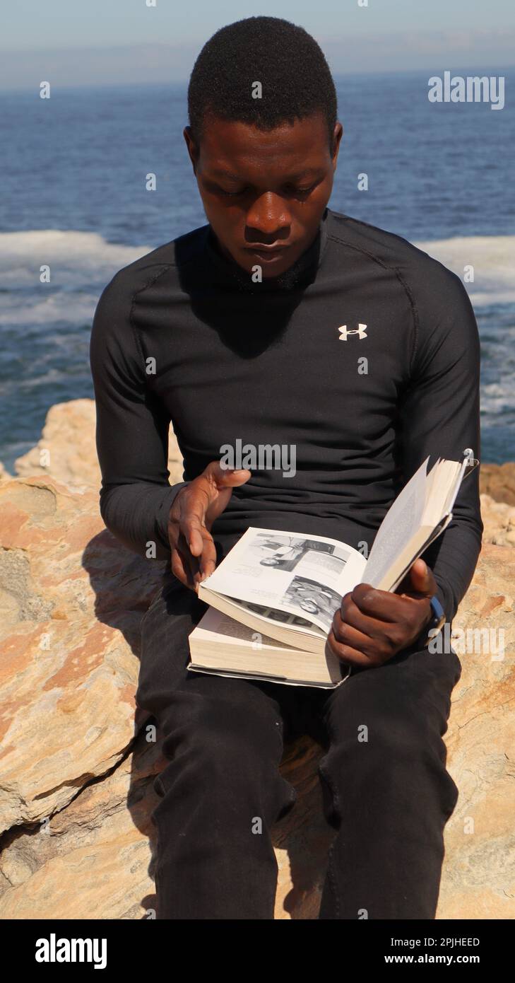 Black African young man reading Nelson Mandela's book sitting on the ...