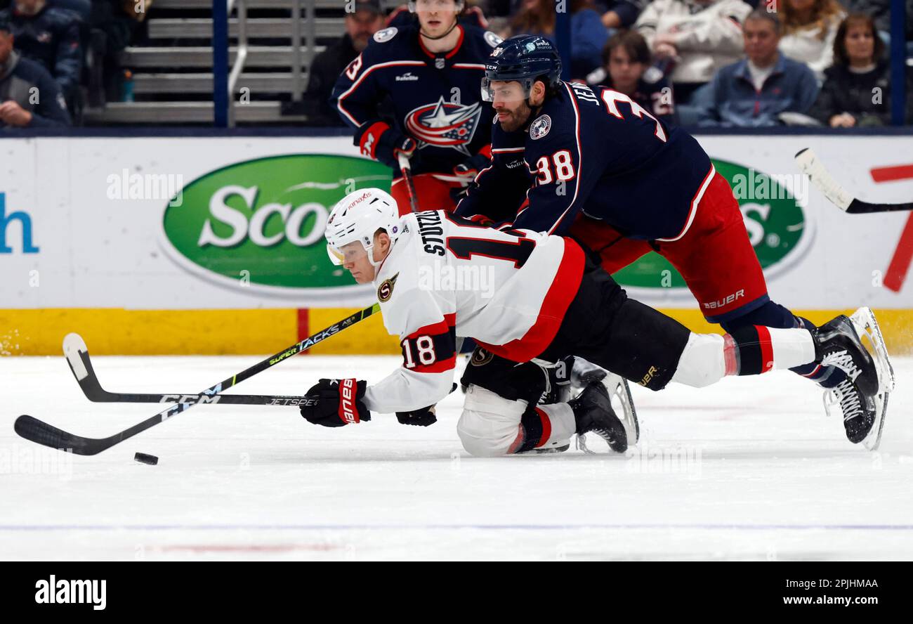 Columbus Blue Jackets forward Boone Jenner, right, reaches for the puck ...