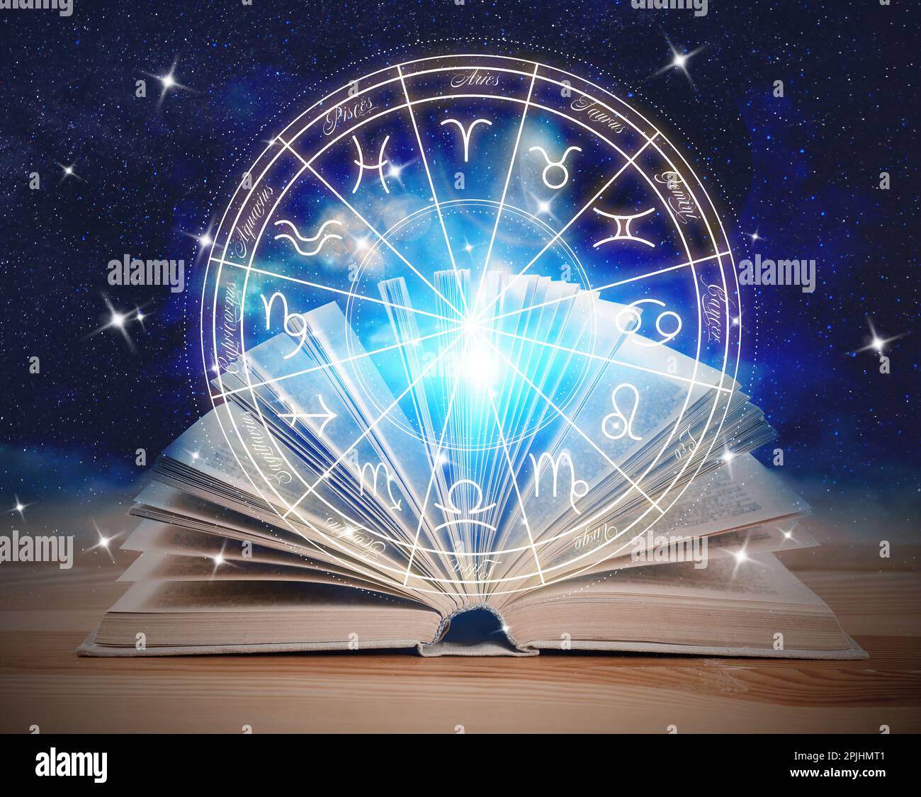 Open book on wooden table, illustration of zodiac wheel with ...