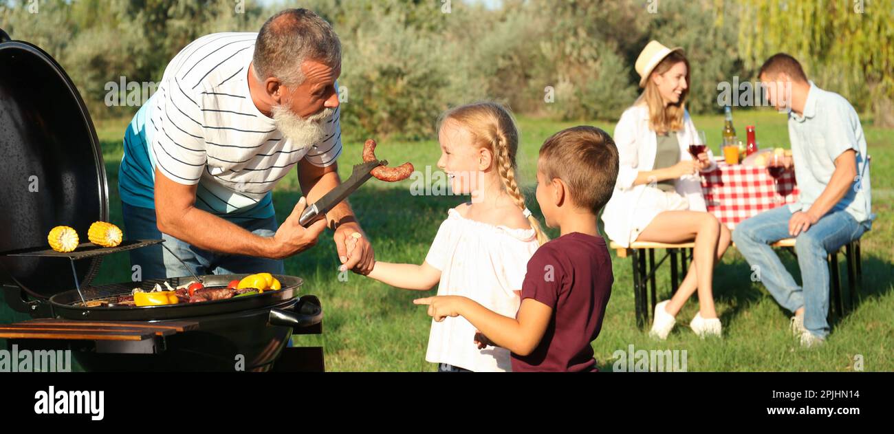 Grandfather with little kids cooking food on barbecue grill and their ...