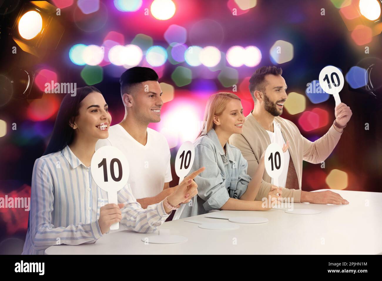Panel of judges holding signs with highest score at table against ...