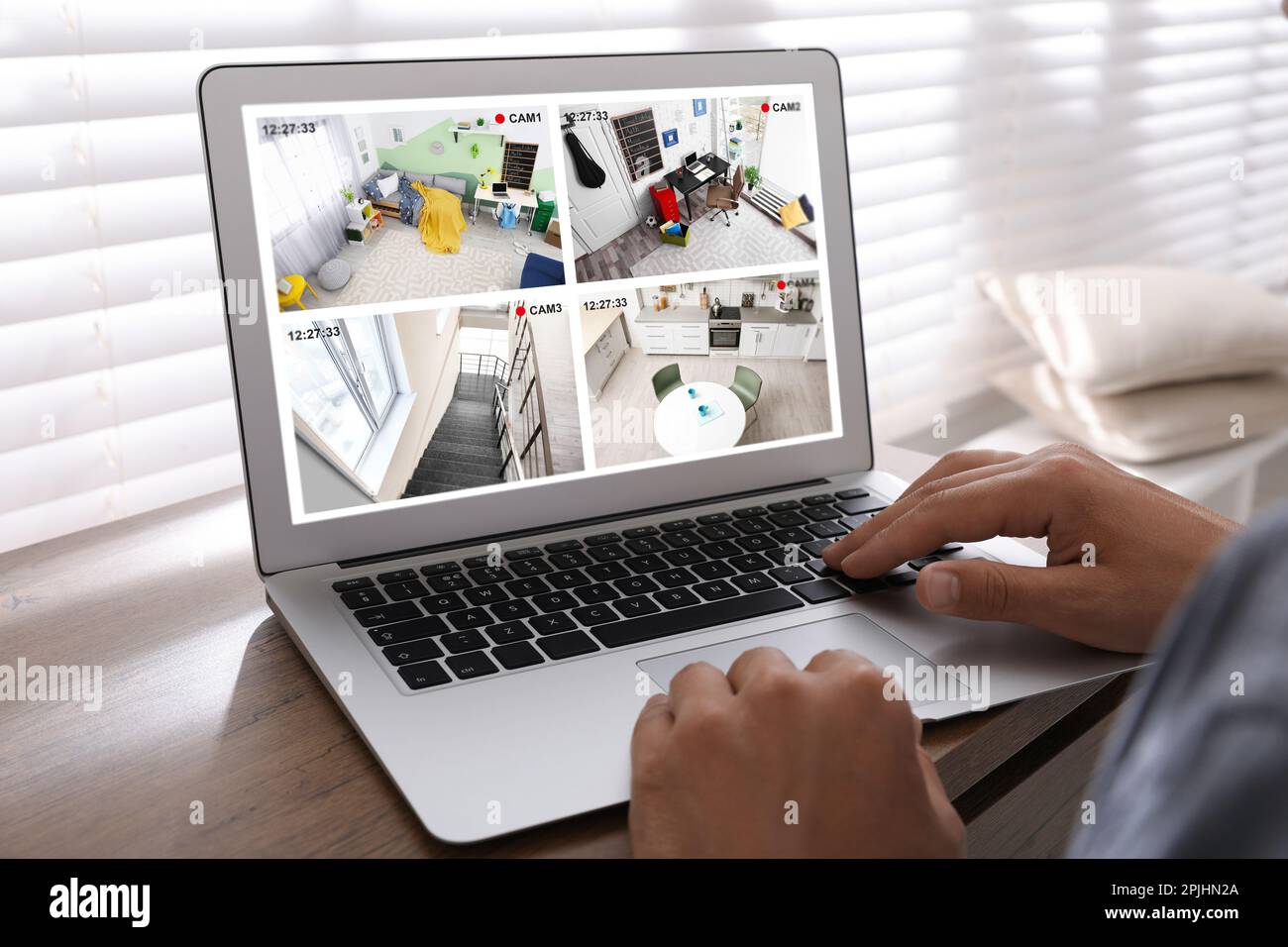 Man monitoring modern CCTV cameras at wooden table, closeup. Smart home ...
