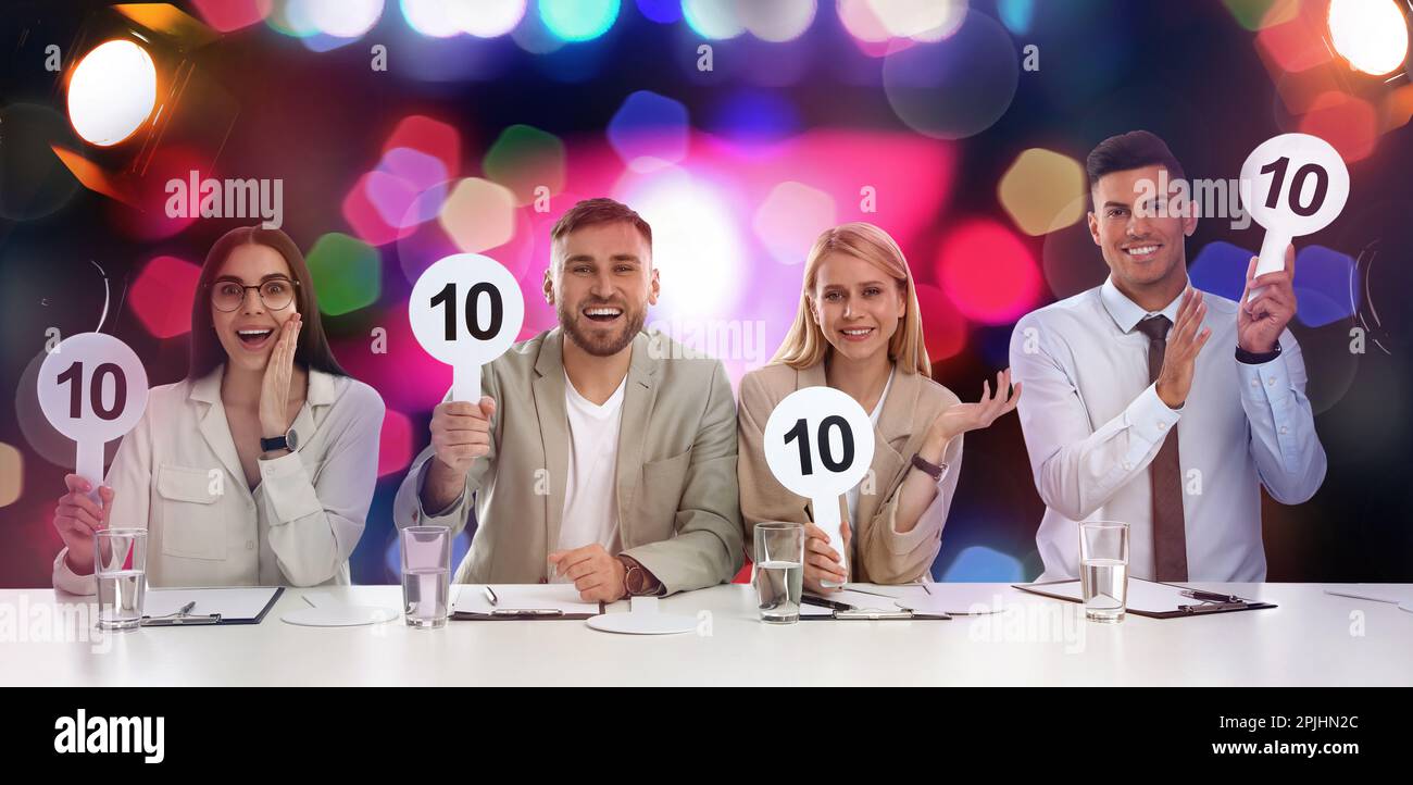 Panel of judges holding signs with highest score at table against ...