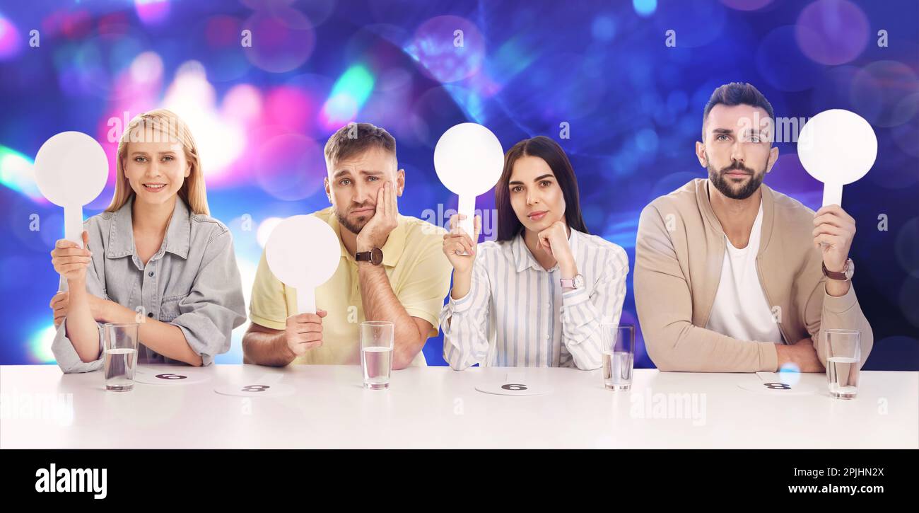 Panel of judges with different emotions holding blank signs at table ...