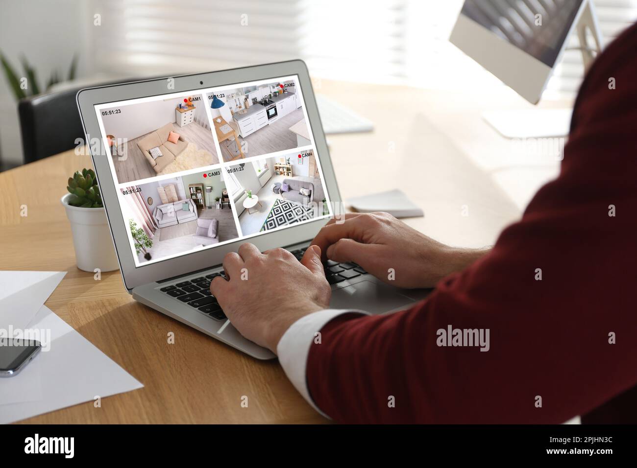 Man monitoring modern CCTV cameras at wooden table, closeup. Smart home ...