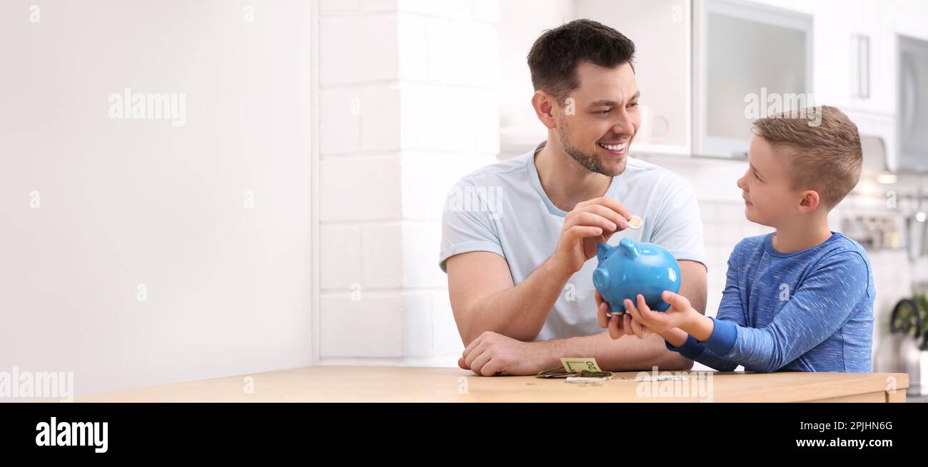 Father and son putting money in piggy bank at home, space for text ...