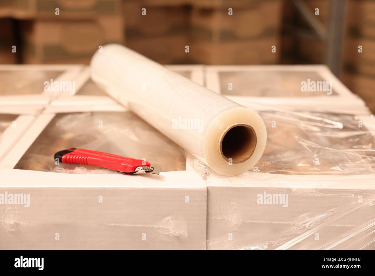 Roll of stretch film and utility knife on wrapped boxes in warehouse ...